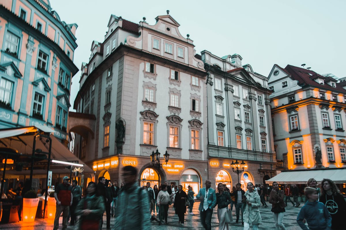 Evening scene showing historic Prague architecture with people walking the streets