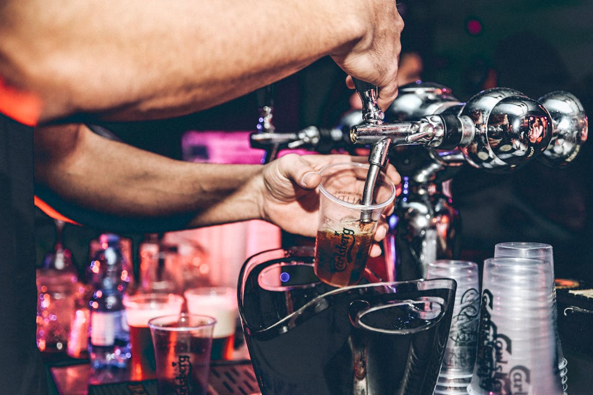 Close-up of a bartender pouring beer into a cup at a bar
