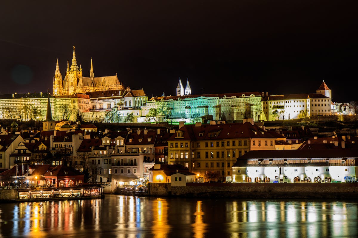 Prague Castle illuminated at night with reflections in the Vltava River