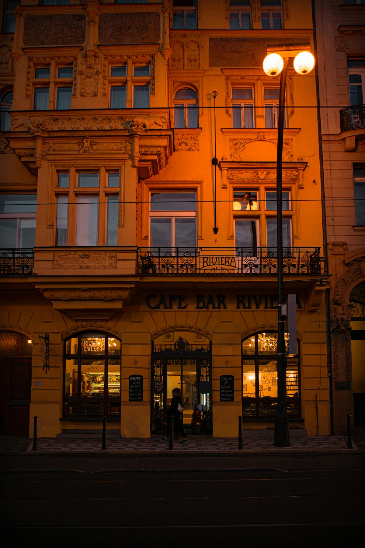 Ornate cafe bar facade in Prague with warm lighting in the evening