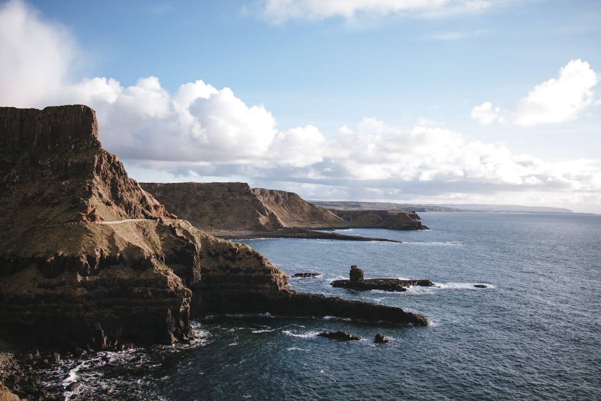 Rocky cliffs washed by calm sea against cloudy sky