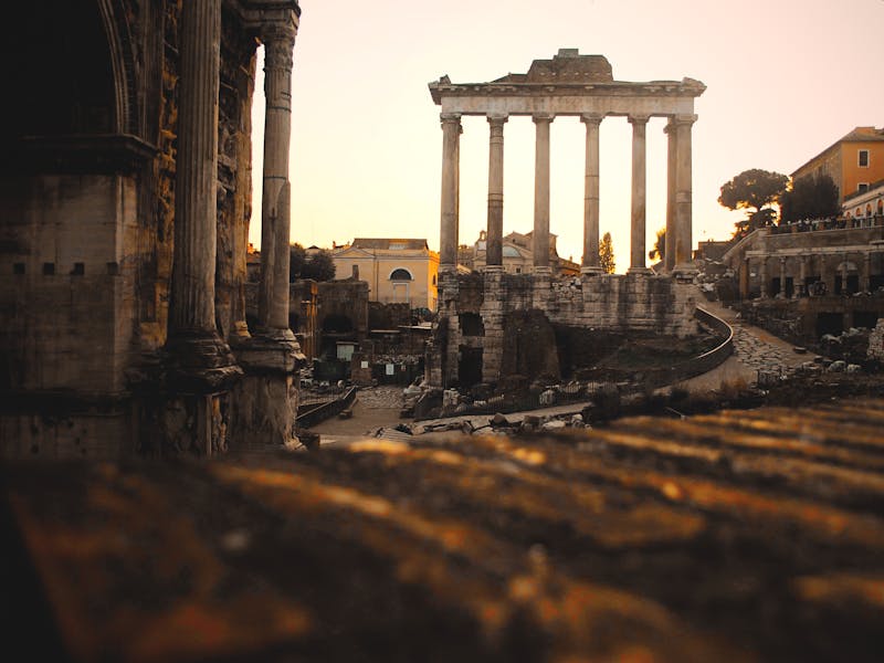 Roman Forum ruins bathed in warm sunset light in Rome Italy