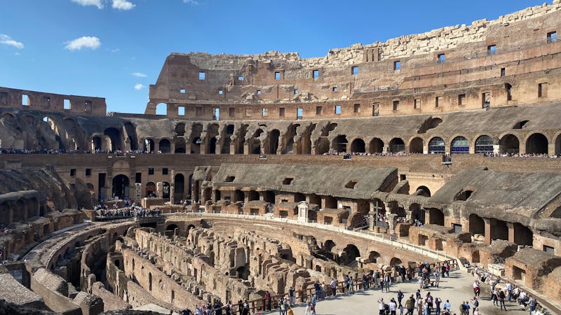 Interior view of the Roman Colosseum filled with travelers on a sunny day