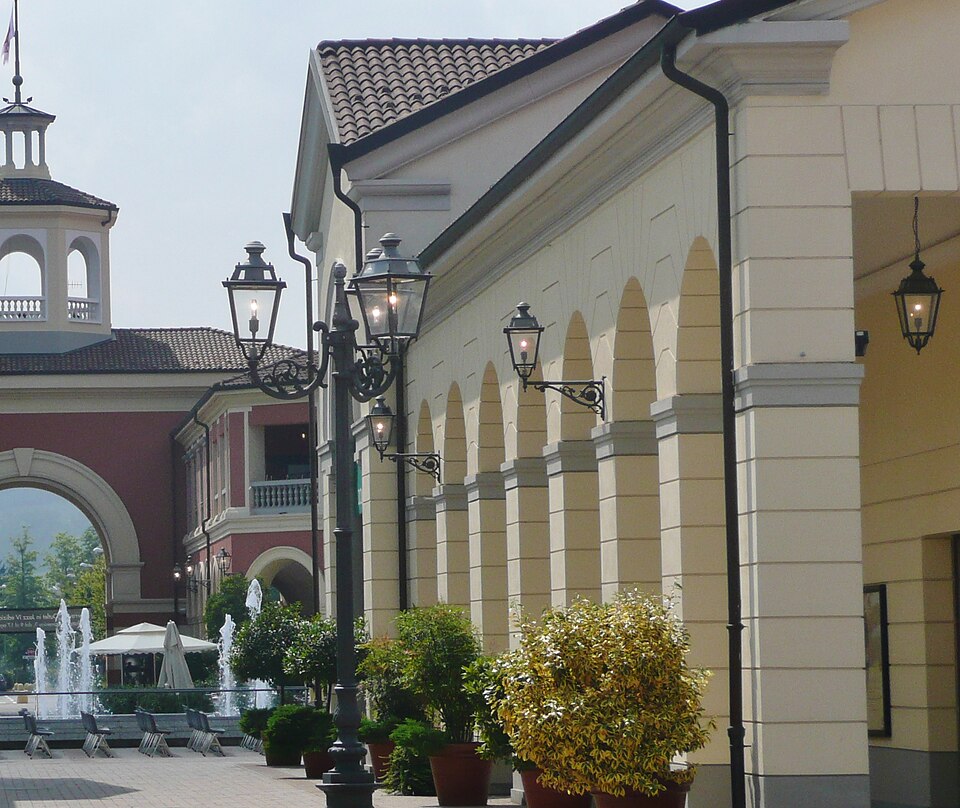 Storefronts at Serravalle Designer Outlet with shoppers walking along the pedestrian path