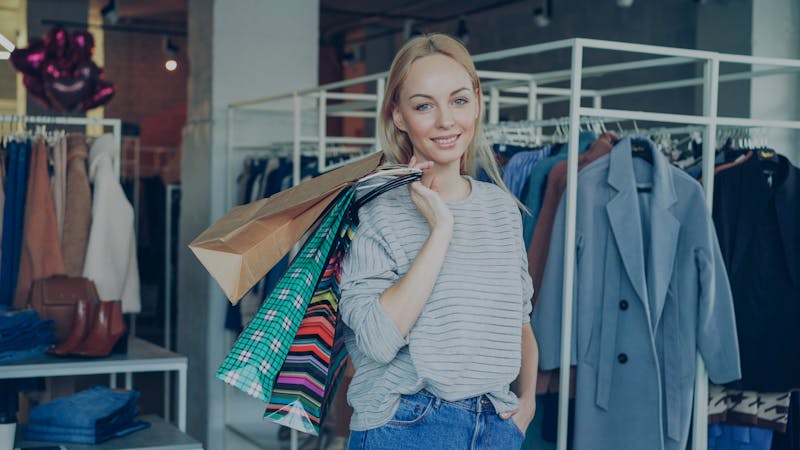 Smiling woman holding shopping bags inside a trendy fashion boutique