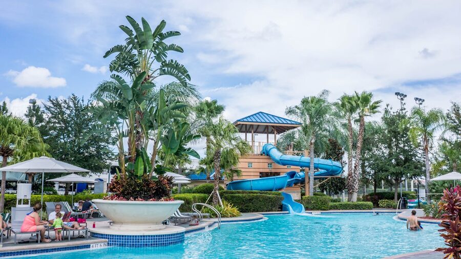 Resort pool area with water slide surrounded by palm trees at tropical location