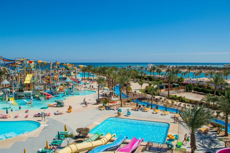 Aerial view of a tropical water park with colorful slides and pools beside the ocean
