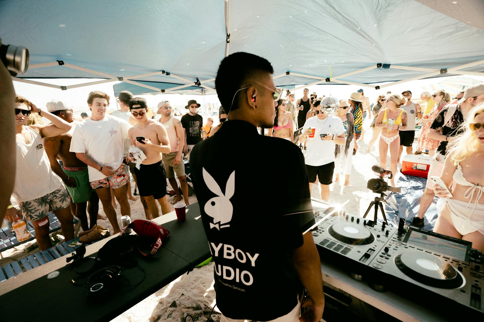 DJ performing for a crowd of people dancing at a beach party