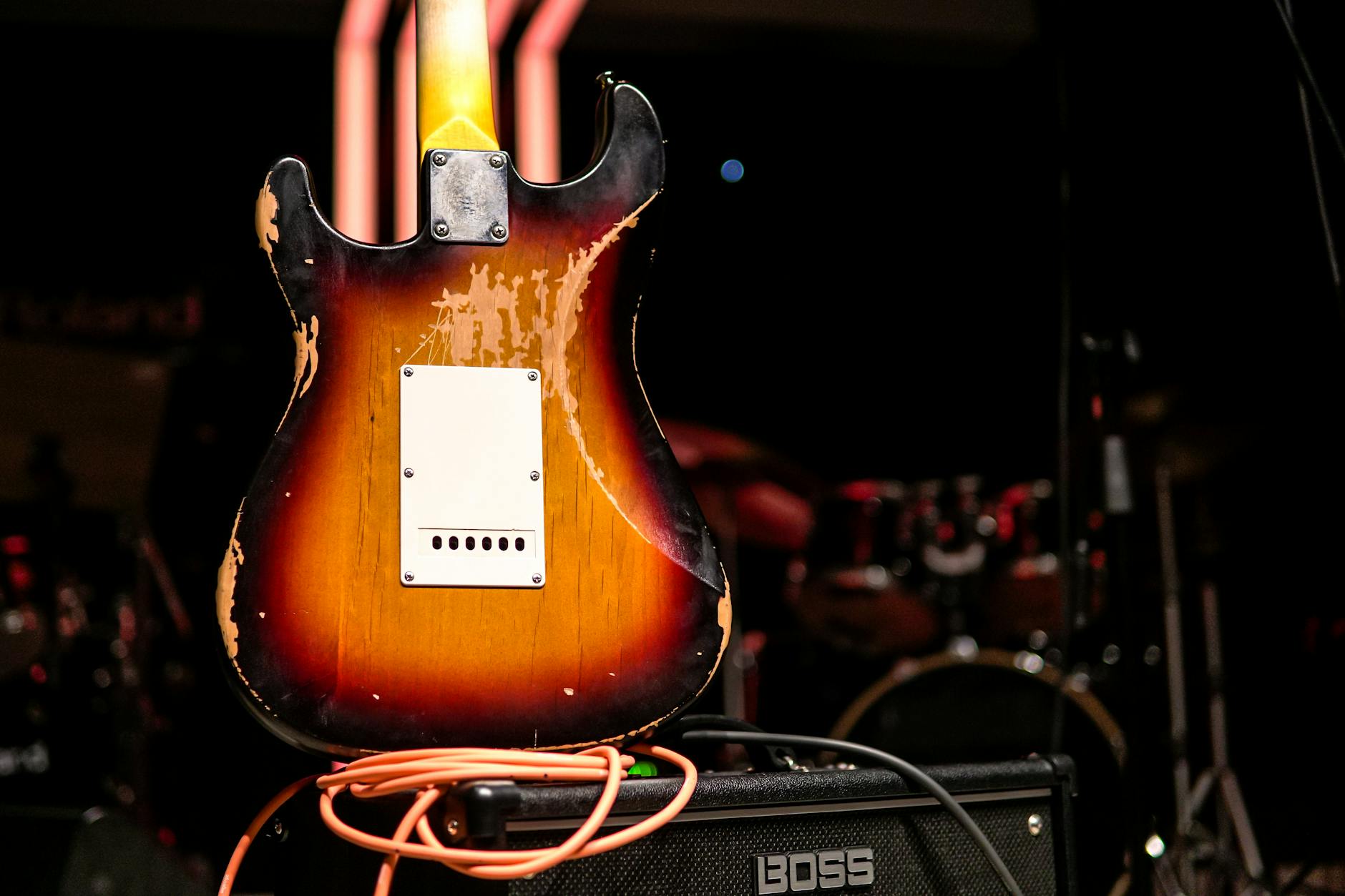 Worn electric guitar with amplifier on a dimly lit stage