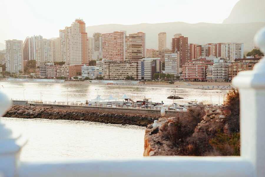 Beautiful sunset over Benidorm coastline with illuminated high-rise buildings and calm Mediterranean sea