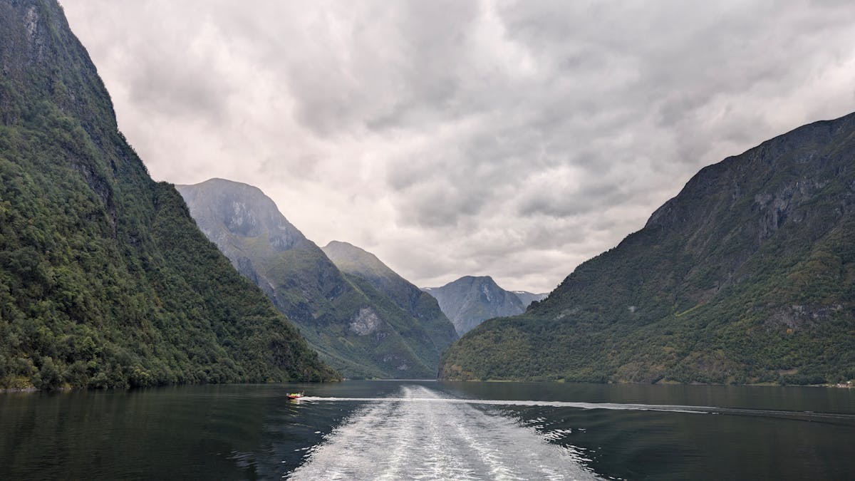 Boat sailing through Bergen fjord with mountains and dramatic sky in background