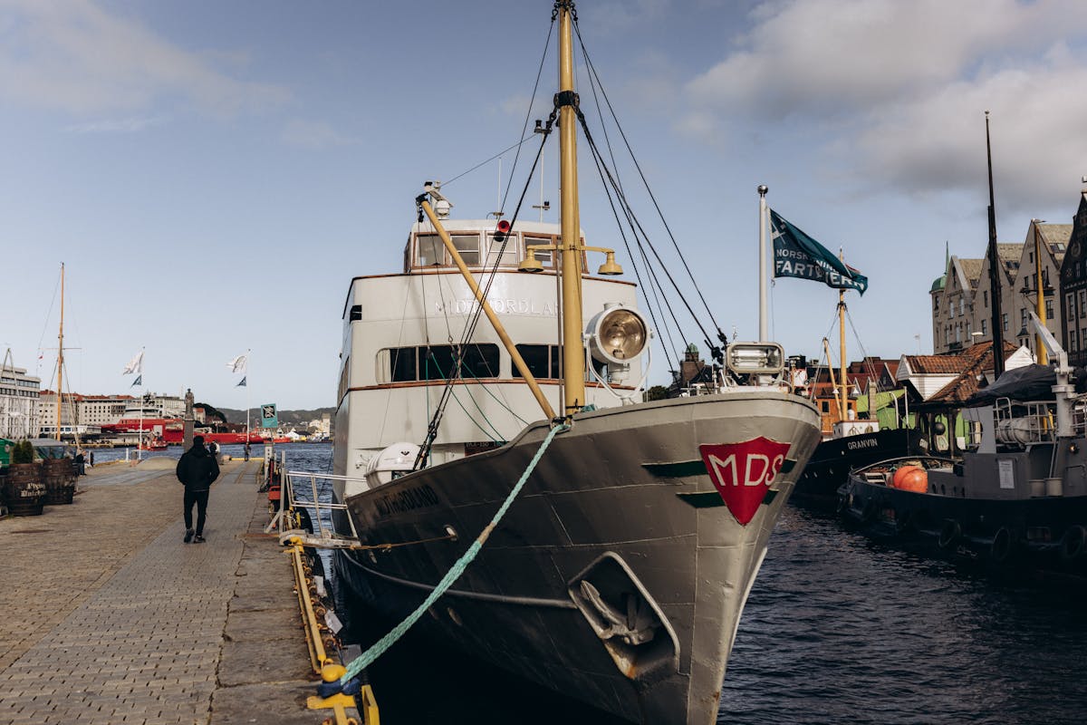 Classic ship docked at Bergen harbor with waterfront buildings
