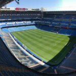 Aerial view of the Santiago Bernabeu Stadium showing the green pitch and stands on a sunny day in Madrid