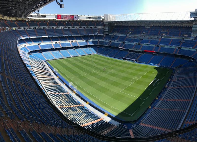 Aerial view of the Santiago Bernabeu Stadium showing the green pitch and stands on a sunny day in Madrid