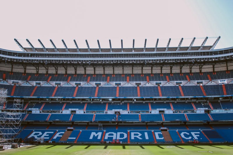 Empty blue seats in the stands of Santiago Bernabeu Stadium with the green pitch visible below