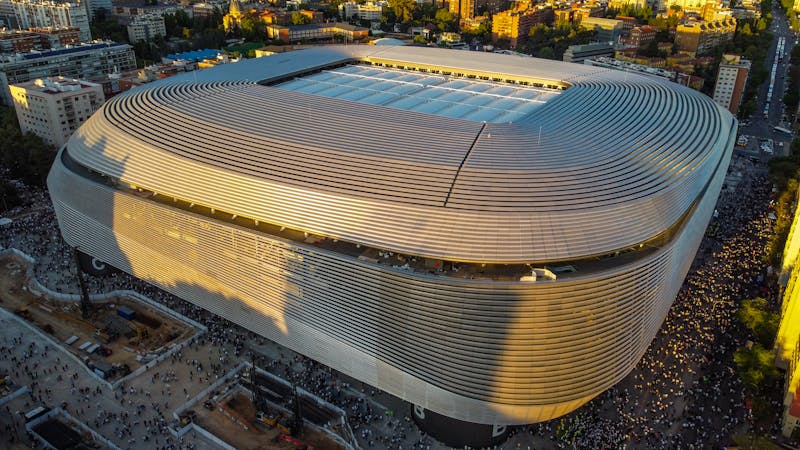The modern curved exterior of the renovated Santiago Bernabeu Stadium in Madrid at sunset
