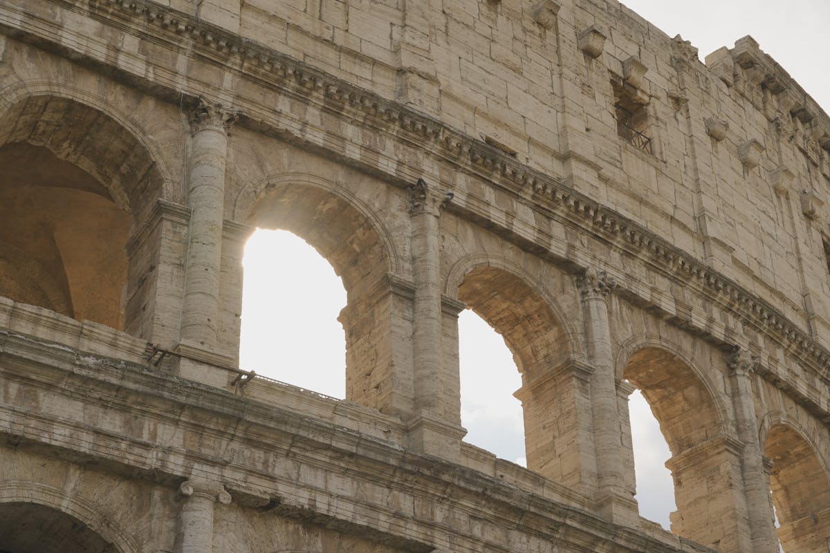 Close-up of Colosseum arches with sunlight streaming through ancient Roman stonework