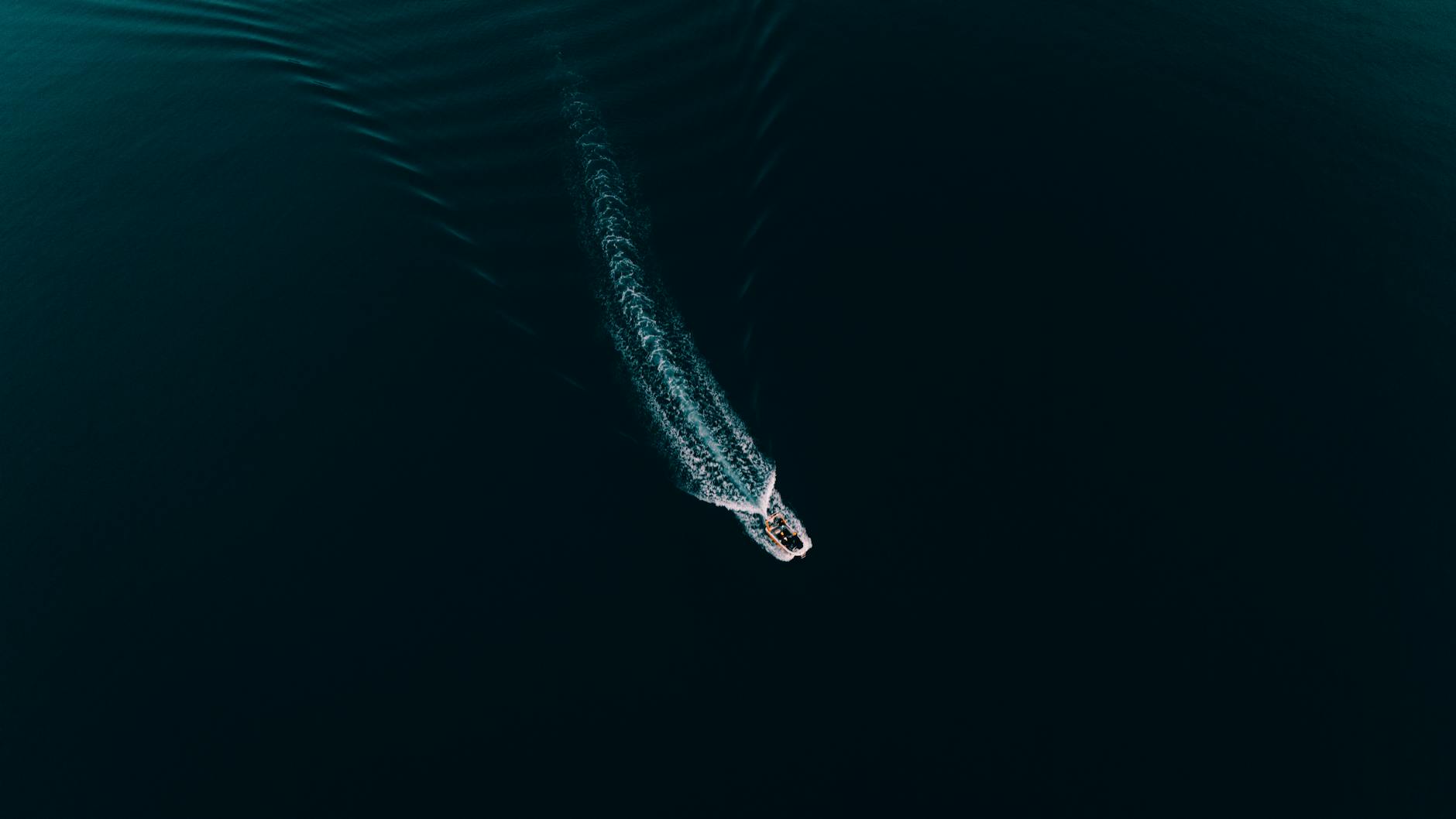 White wake of a boat cutting through deep blue ocean water