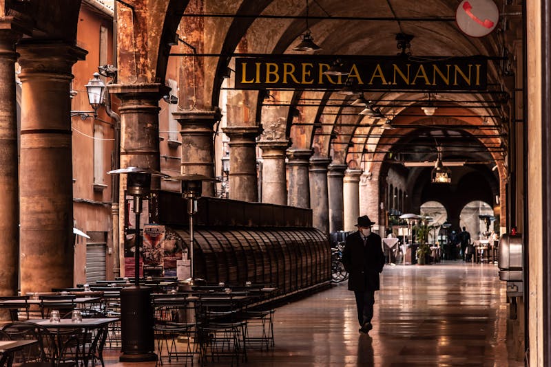 A person walking under the historic arched porticoes in Bologna Italy