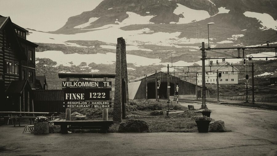 Black and white photo of Finse railway station with snowy mountains in the background.