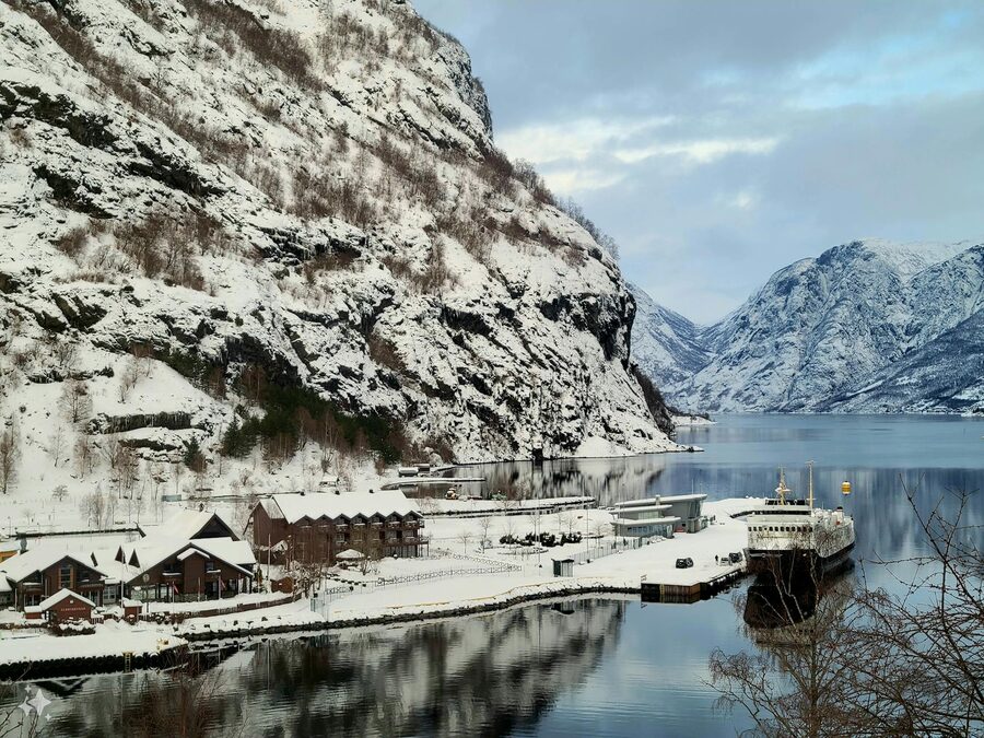Snow-covered port in Flåm, Vestland, Norway reflecting mountains in winter.