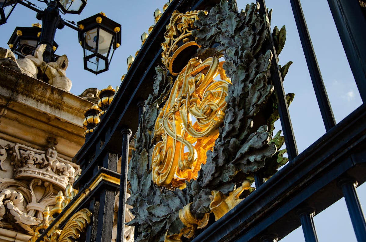 Close-up of gilded ironwork at Buckingham Palace gates in London showcasing intricate royal design