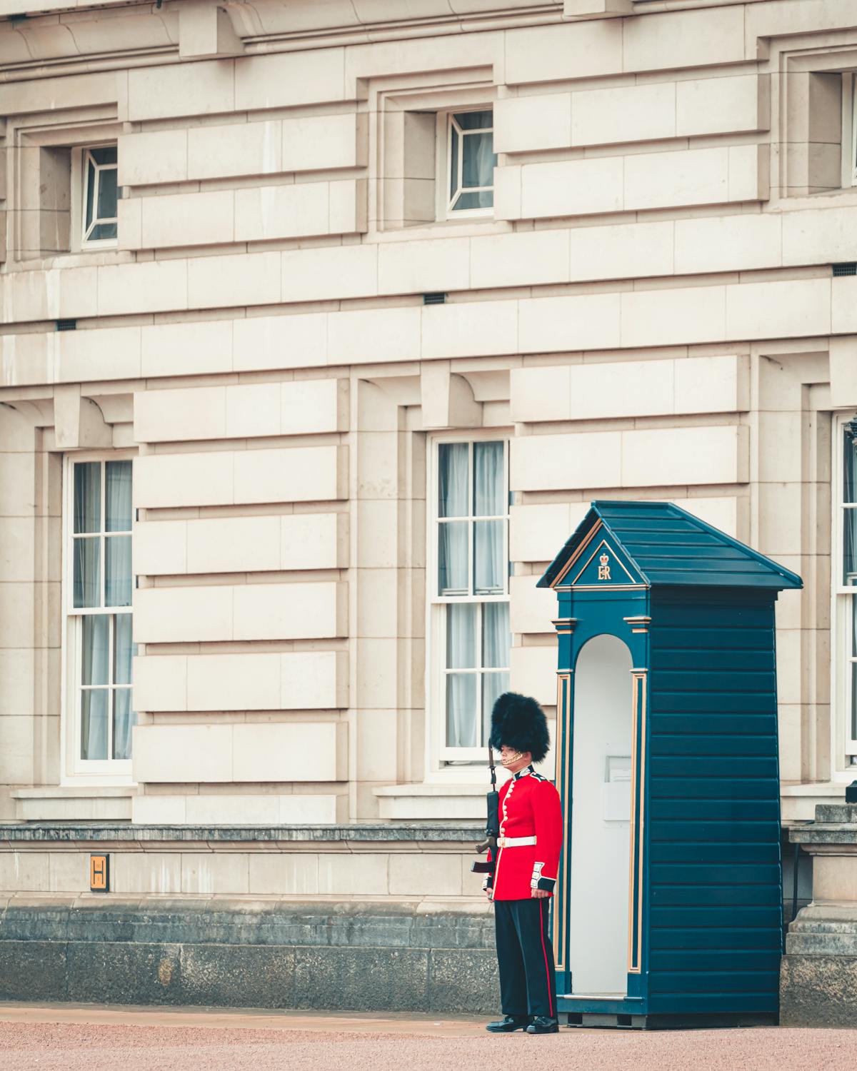 A royal guard in traditional red uniform stands at his sentry post outside Buckingham Palace England