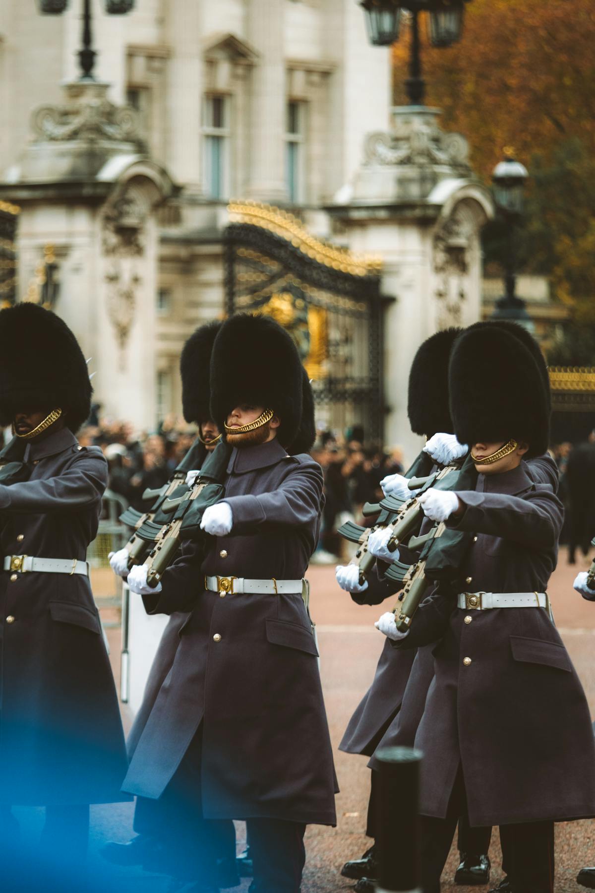 Guards in traditional red uniforms perform ceremonial duties at Buckingham Palace iconic London scene