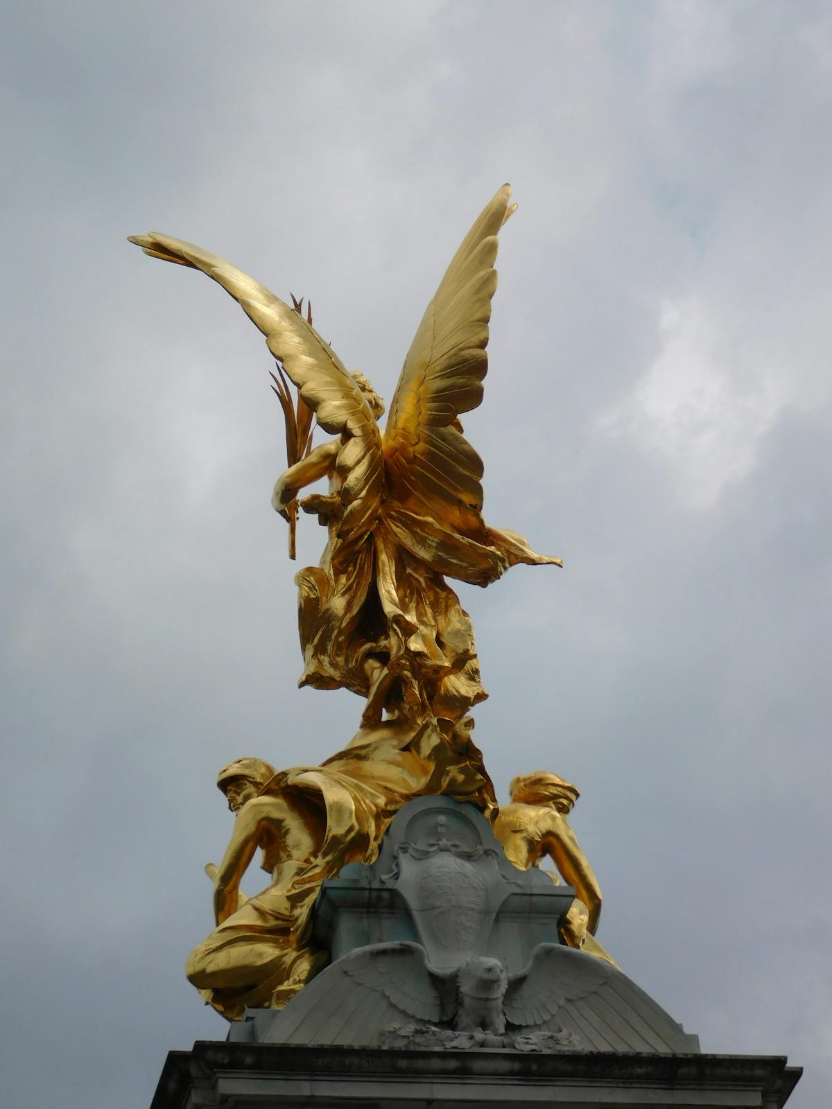 Golden statue atop the Victoria Memorial with dramatic sky near Buckingham Palace