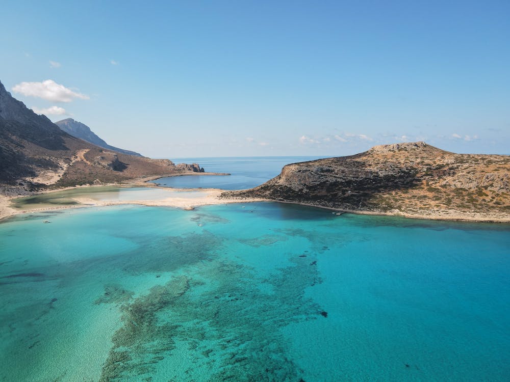 Breathtaking aerial capture of a turquoise lagoon and rugged island coastline under clear blue skies.