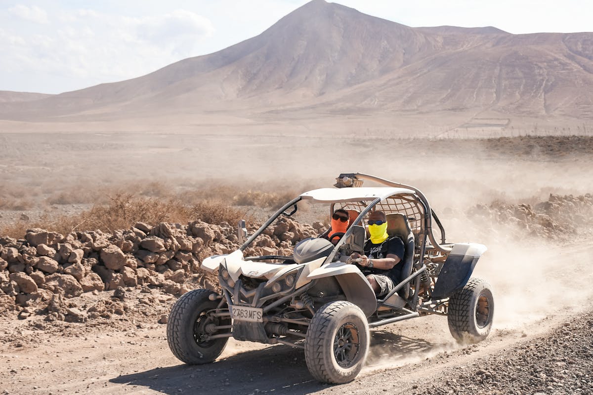 Dune buggy racing across rugged volcanic desert landscape