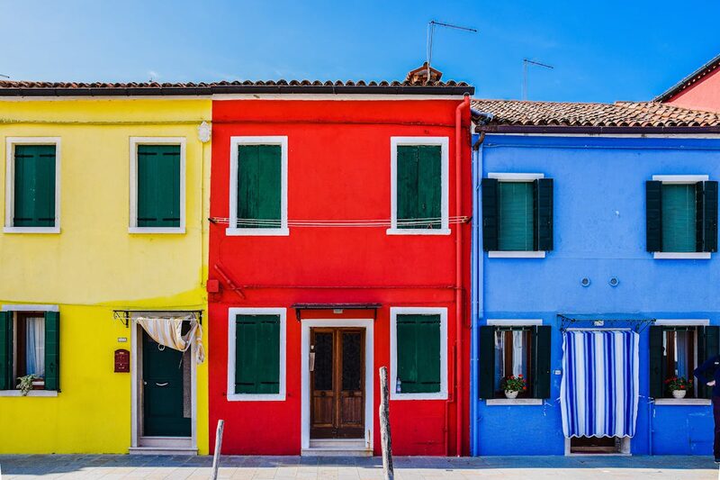 Brightly painted houses in Burano reflected in the calm canal water