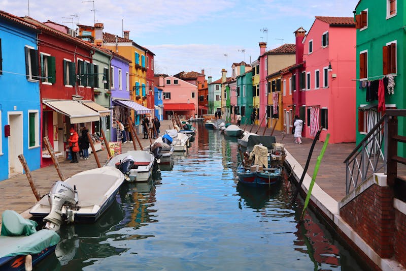 Colorful houses and boats lining a canal in Burano, Venice, Italy