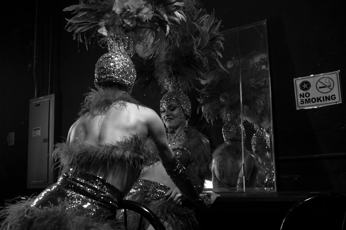 A cabaret dancer in a feathered headdress and sequined costume backstage
