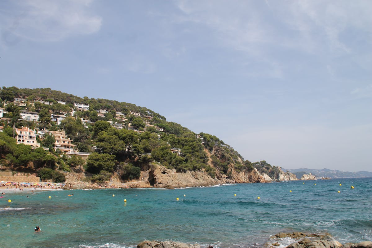 Clear blue waters at Cala Canyelles beach on the Costa Brava with green hillsides