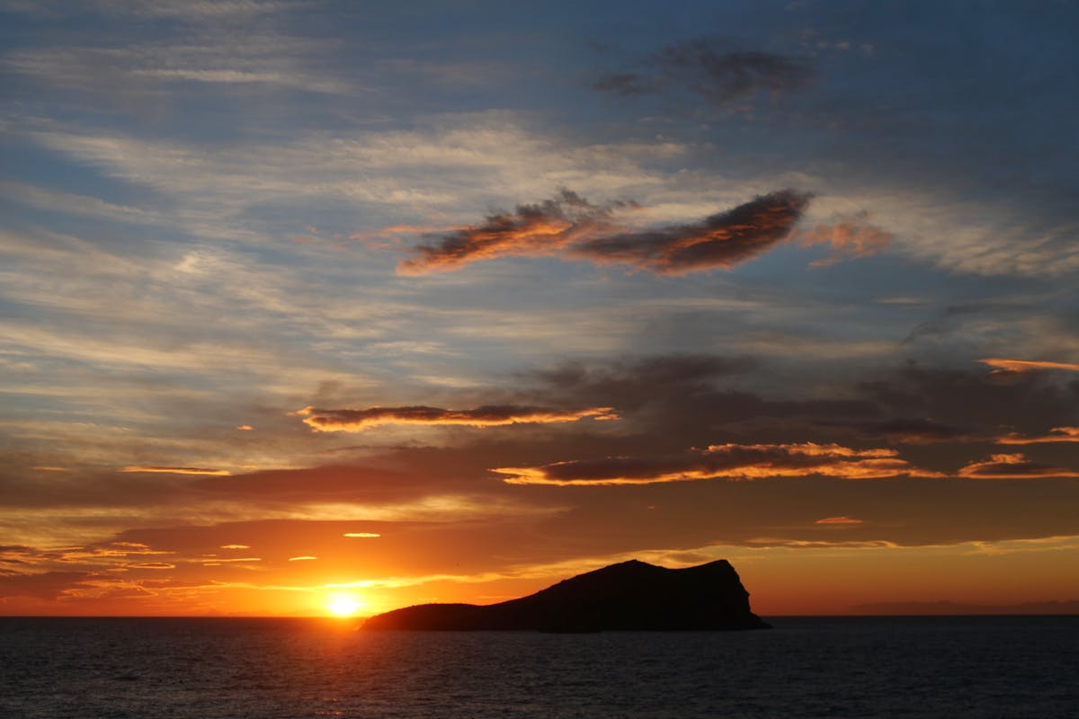 Vibrant orange and pink sunset sky over Cala Comte beach in Ibiza with sea view