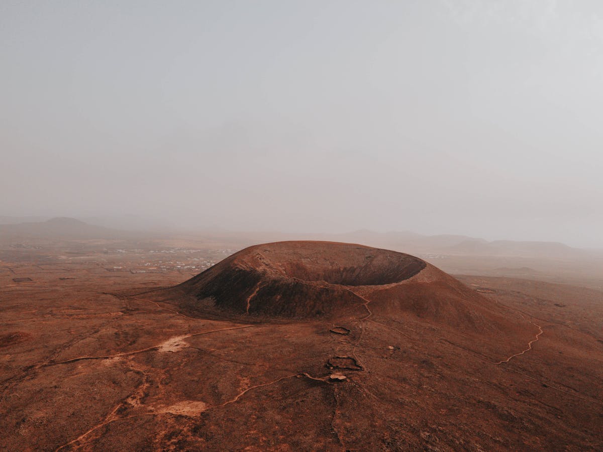 Aerial view of Calderon Hondo volcano crater amid foggy arid landscape in Fuerteventura