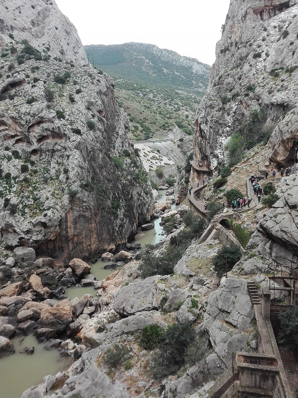 Wooden boardwalk path along the cliff face at Caminito del Rey with the Guadalhorce River far below