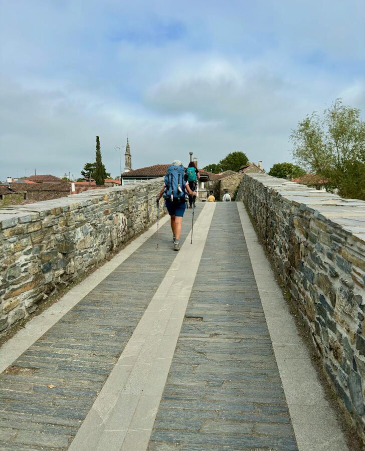 Two hikers with backpacks on an ancient stone pathway on the Camino