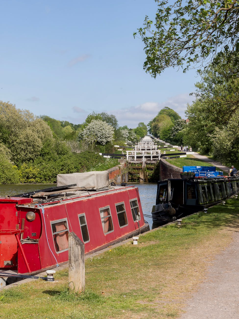 Narrowboats lined up at a canal lock on a sunny day in England