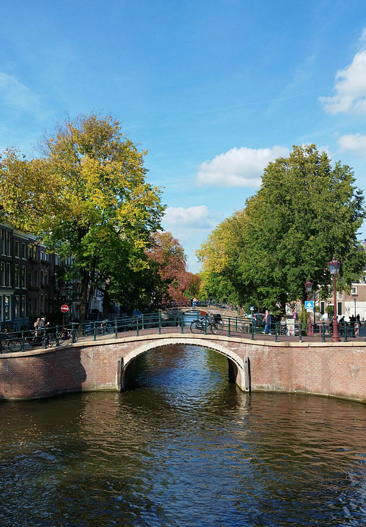 Picturesque canal bridge in Amsterdam surrounded by colorful autumn foliage