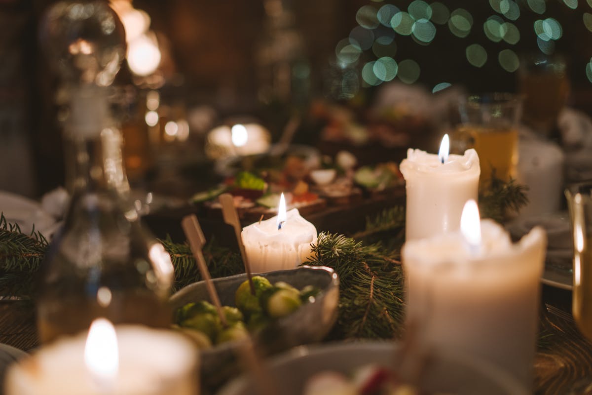 Close-up of candles and food on a warmly lit dinner table