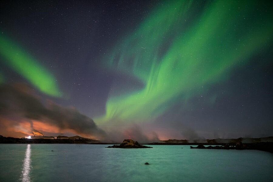 Striking northern lights dancing over the serene lake in Keflavik, Iceland.
