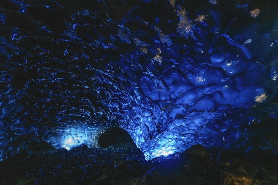 Striking view inside a naturally lit blue ice cave with textured walls.