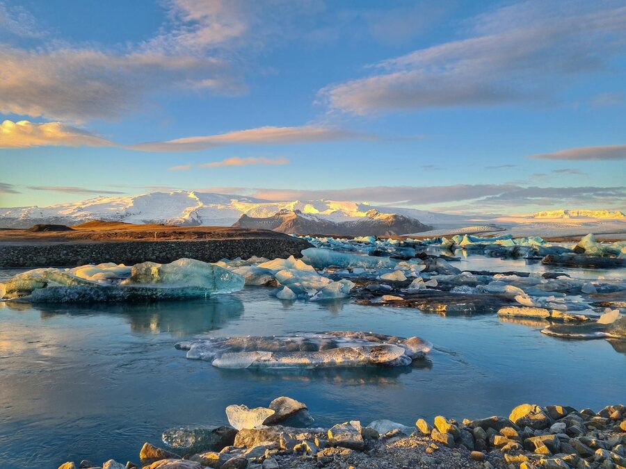 Striking view of icebergs and mountains at sunrise in a serene glacial lagoon.