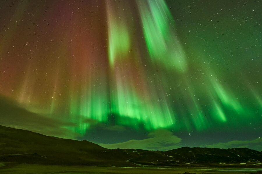 Striking view of the Aurora Borealis over ReykjahlÃ­Ã°, Iceland's night landscape.