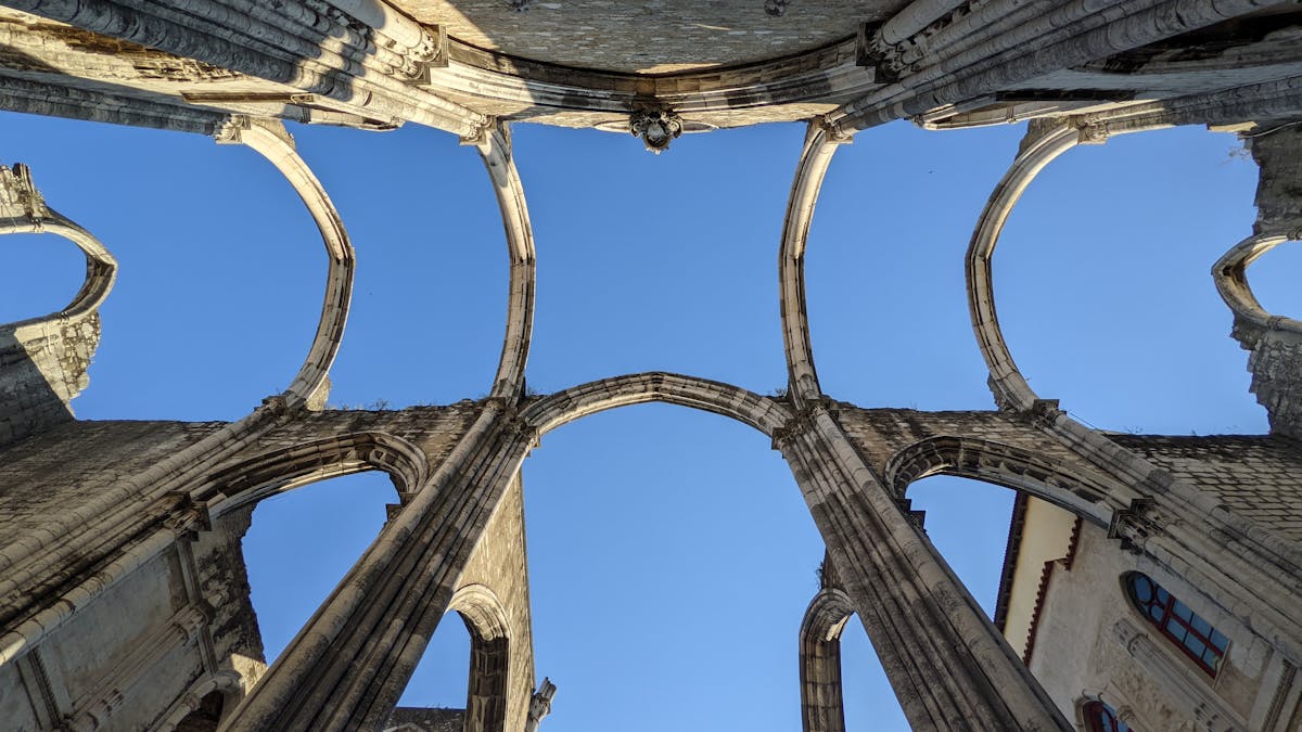 The Gothic arches of the Carmo Convent ruins in Lisbon against a blue sky