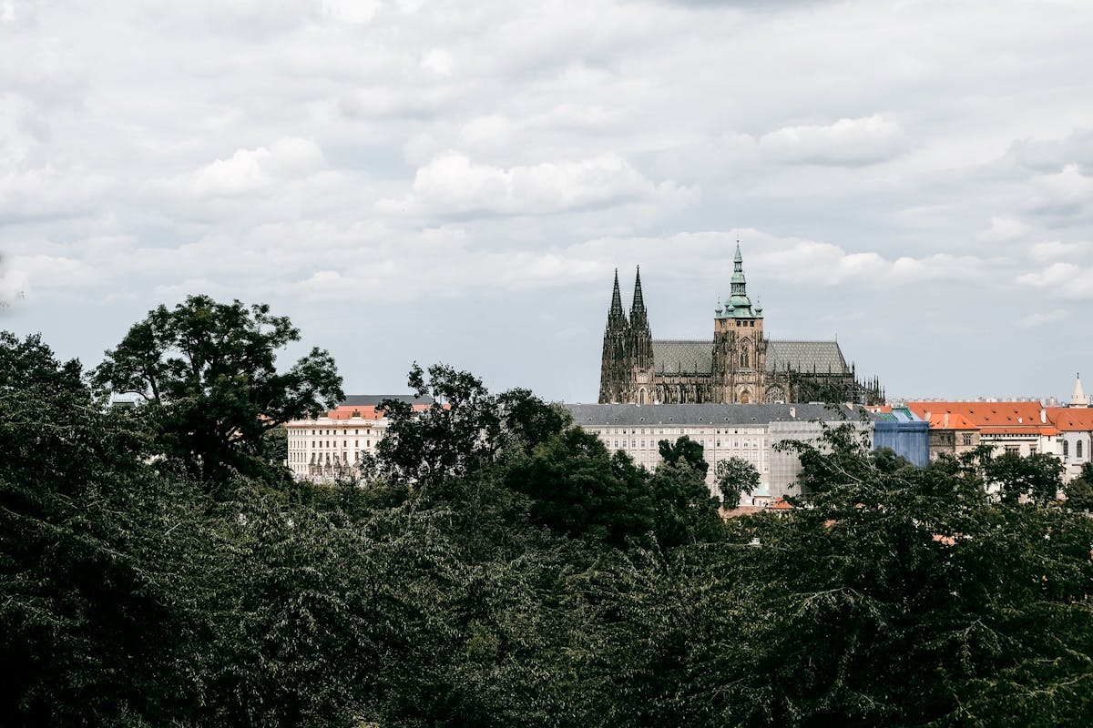 A picturesque view of Prague Castle surrounded by lush green trees