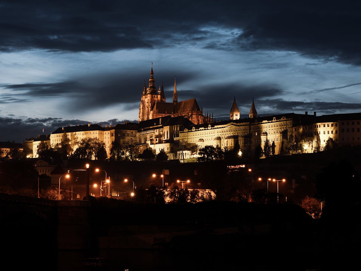 Prague Castle lit up at night with city buildings in the foreground