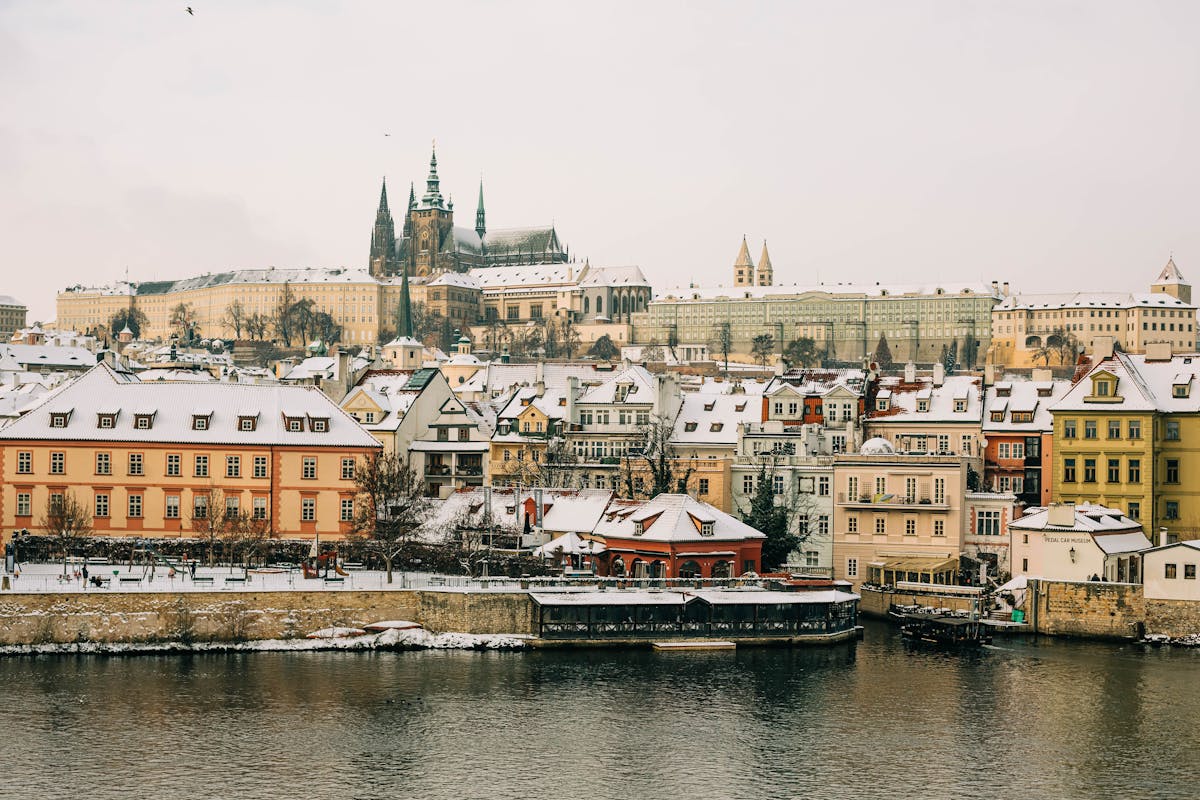 Winter view of Prague Castle and the Vltava River with snow on the rooftops